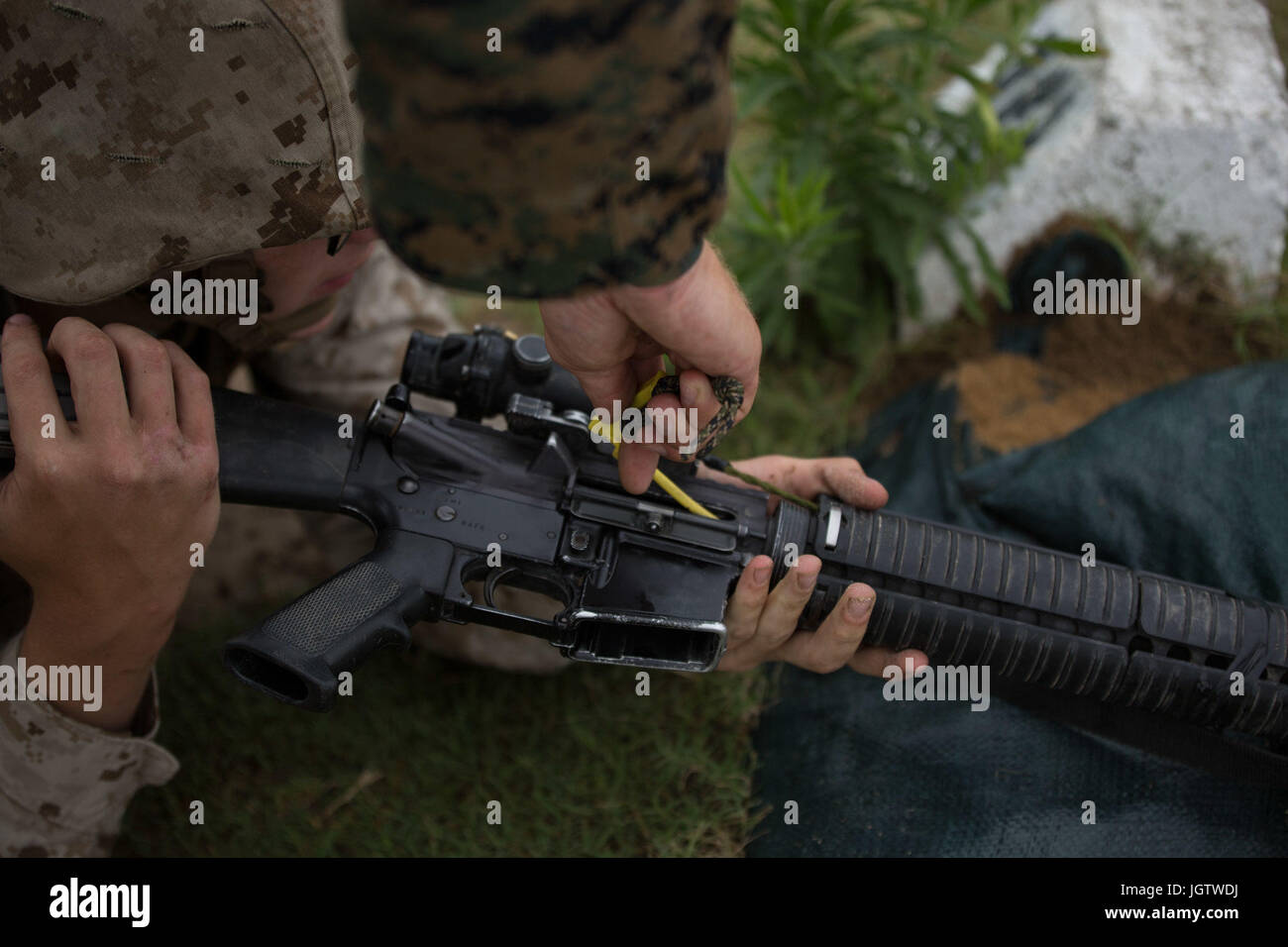 A marksmanship coach clears a recruit’s rifle during combat ...