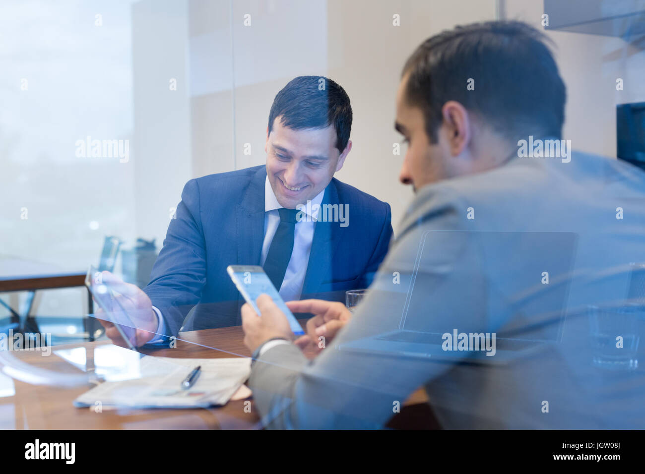Two young businessmen using smart phones and touchpad at meeting Stock ...