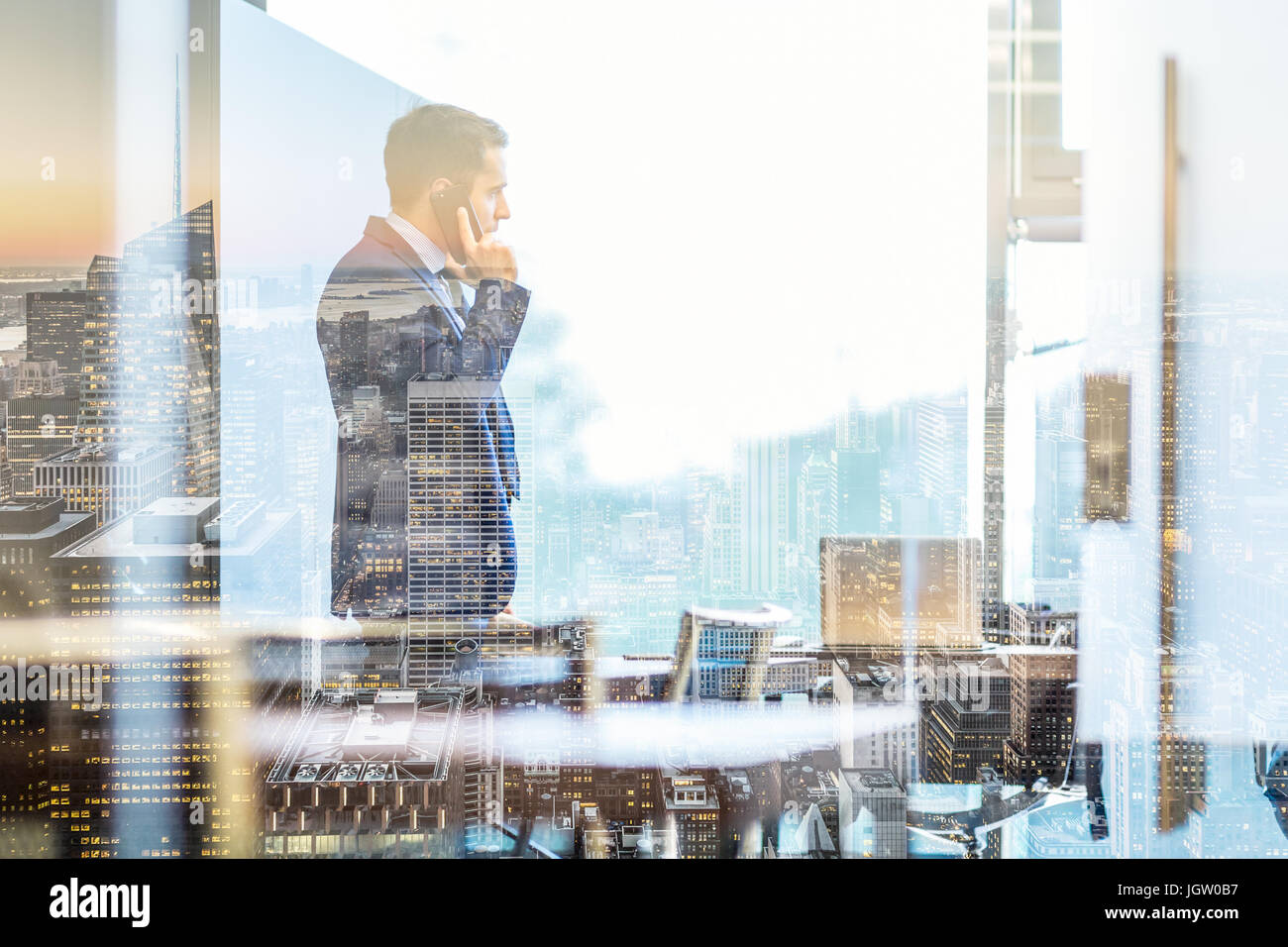 Businessman talking on a mobile phone while looking through window in ...