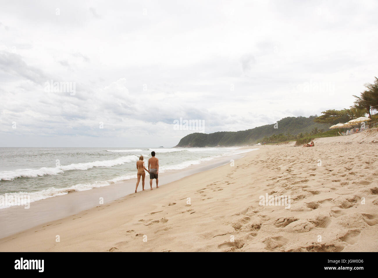 Beach couple walking green hill hi-res stock photography and images - Alamy