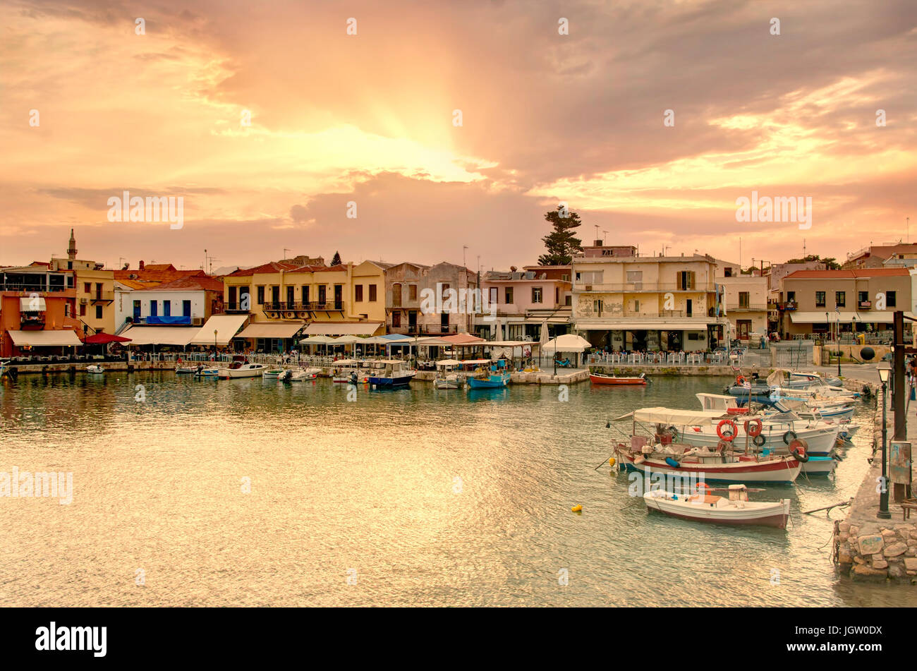Rethymno old port with bars and restaurants lit with warm sunlight ...