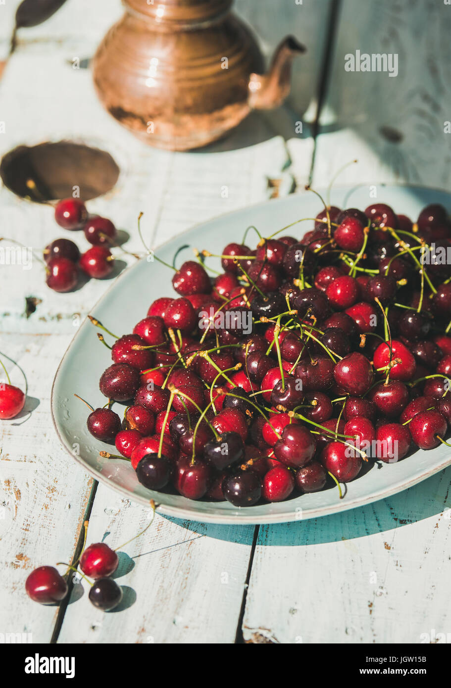 Plate of sweet cherries on light blue wooden table background Stock ...