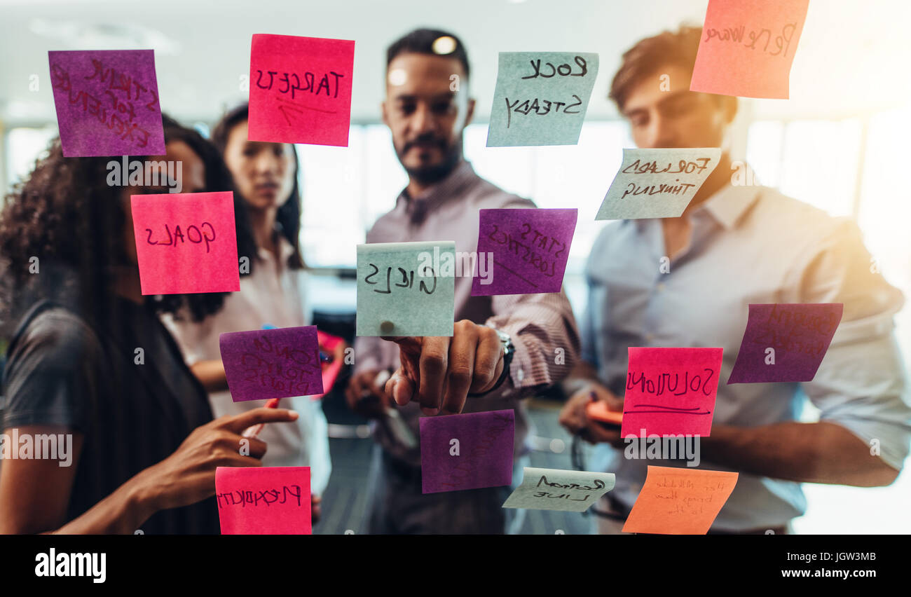 Business investors discussing work looking at the information on sticky ...