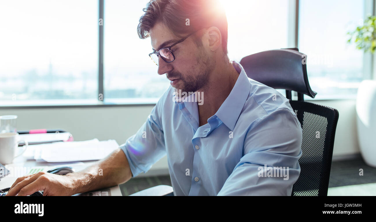 Closeup of businessman sitting at his desk in office. Man wearing ...