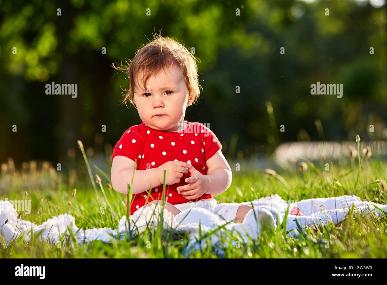 cute adorable nice baby girl in red spring dress smiling sitting under ...