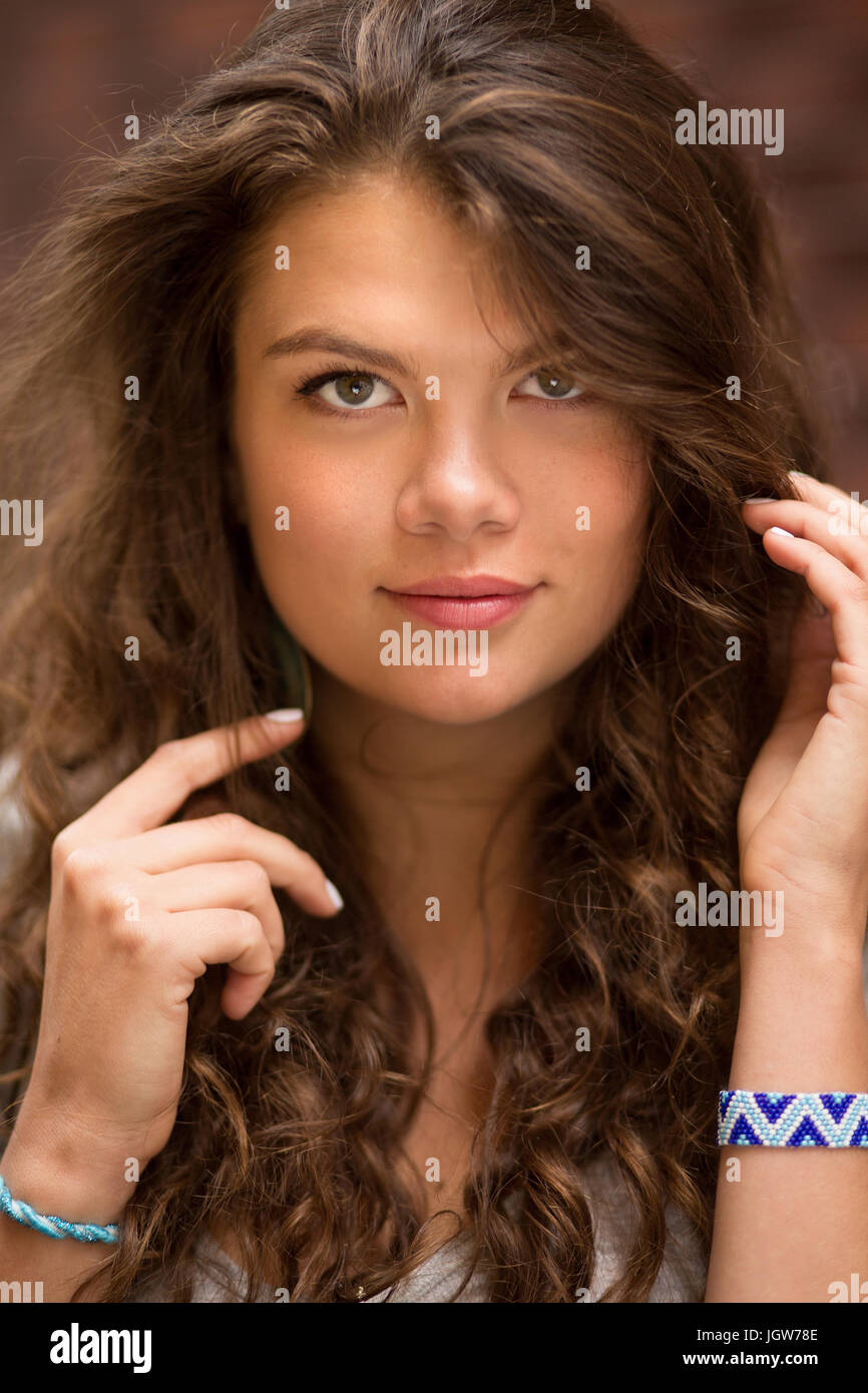 Portrait of young woman with long curly hair, showing her hands Stock ...