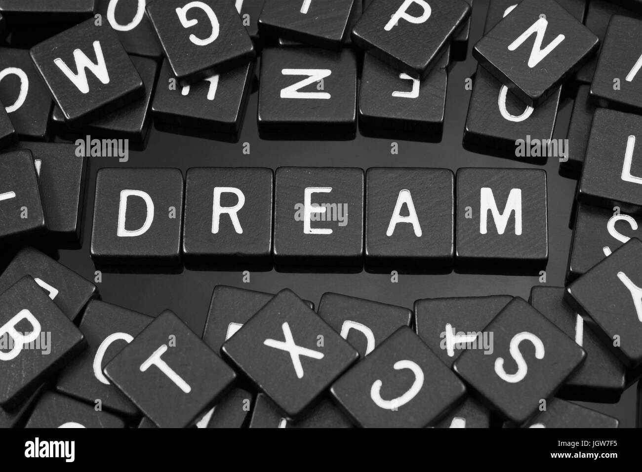 Black letter tiles spelling the word "dream" on a reflective background ...