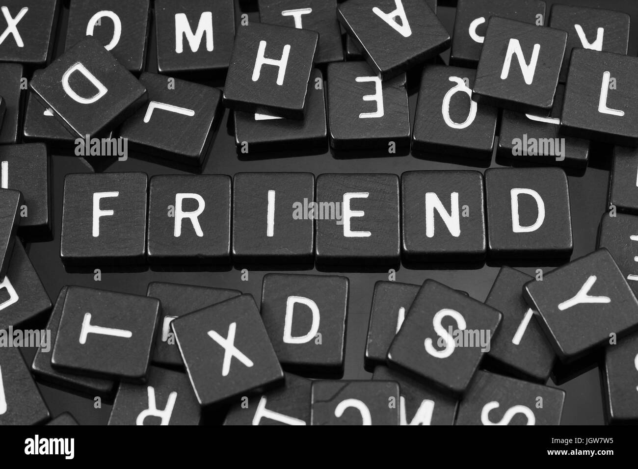 Black letter tiles spelling the word "friend" on a reflective ...