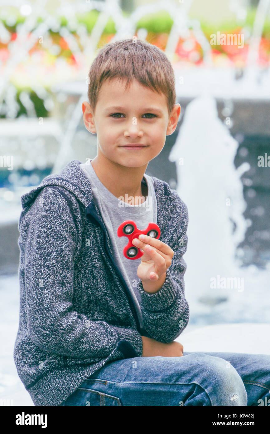 Boy playing with a fidget spinner in city park Stock Photo - Alamy