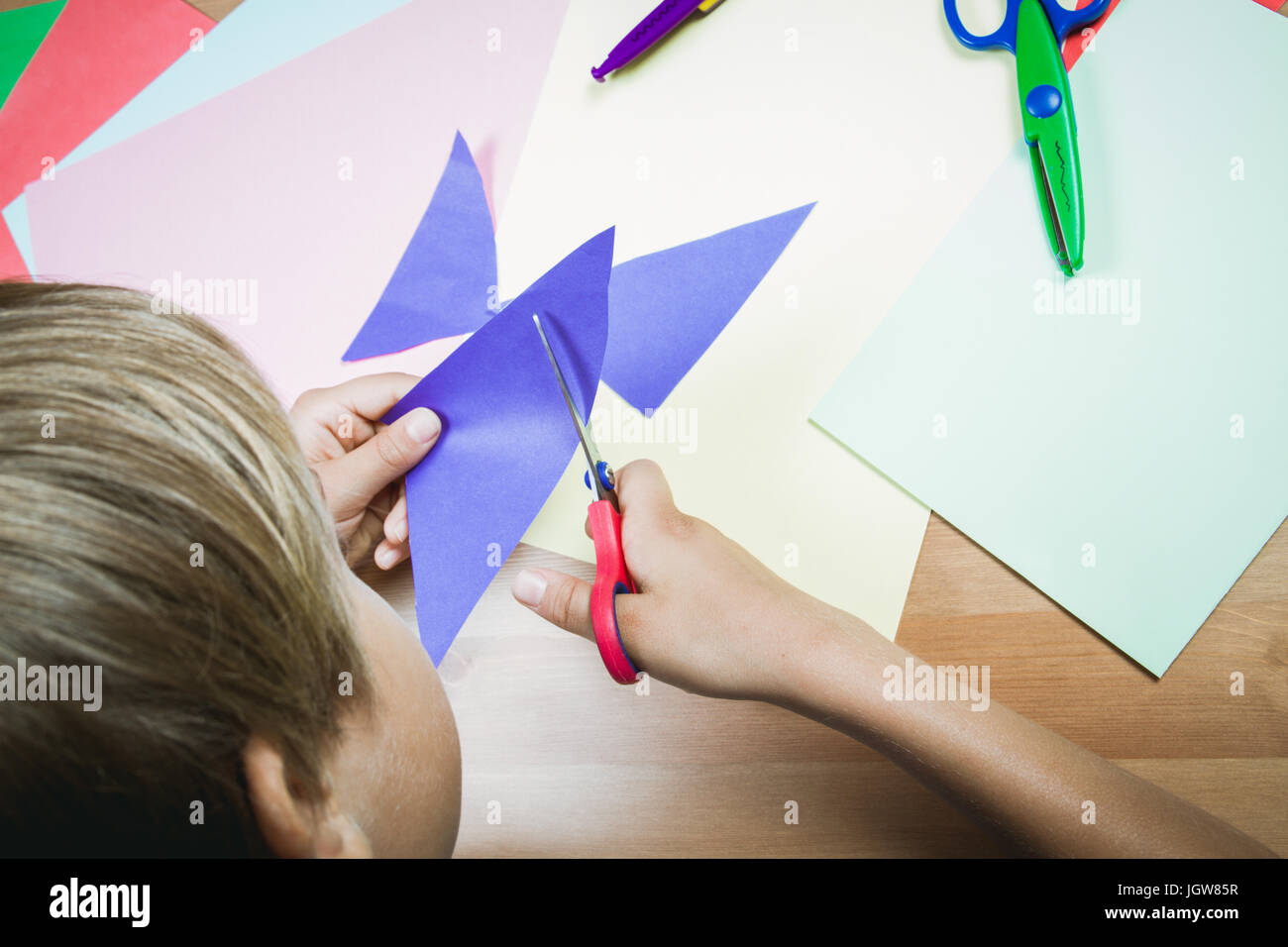 Boy cutting colored paper with scissors at the table Stock Photo - Alamy