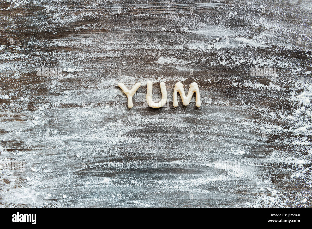 top view of word yum made from cookie dough with flour on wooden ...