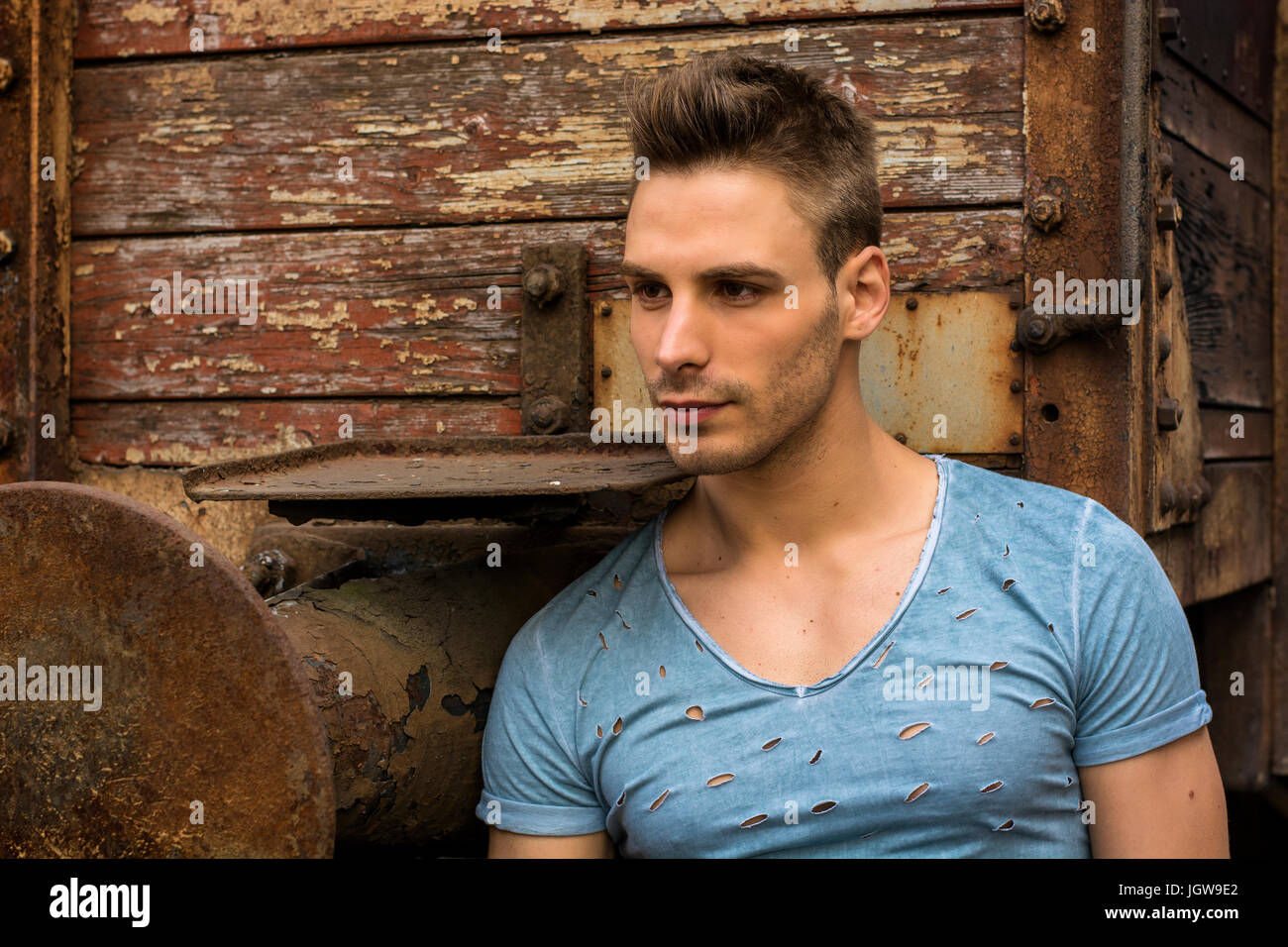 Young man sitting against old rusty train. Looking at camera Stock ...