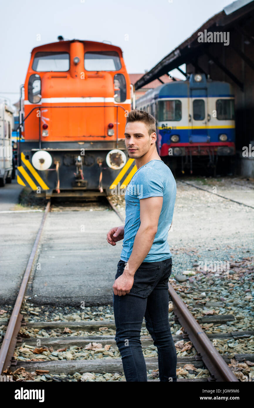 Handsome young man in front of old train, looking away Stock Photo - Alamy