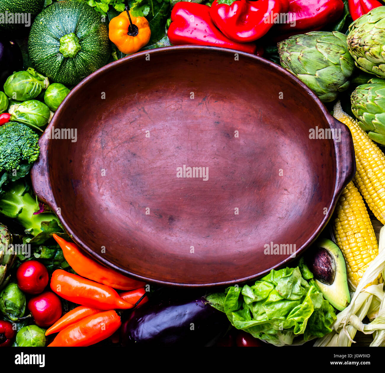 Cooking background concept. Fresh organic vegetables around empty clay ...