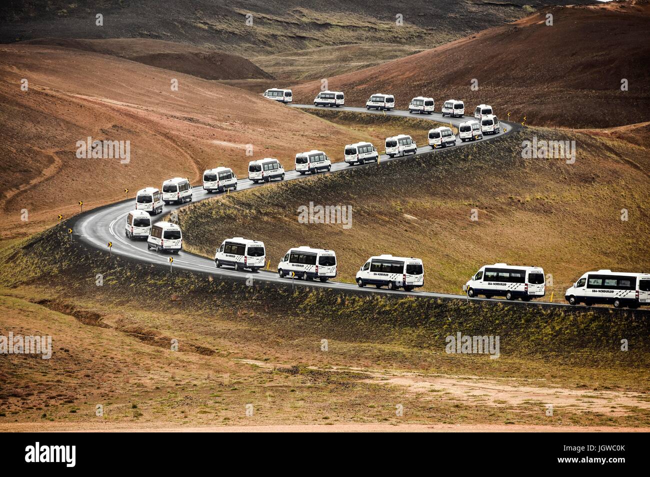 Tour bus vans on a curved road leading through a mountain landscape in ...