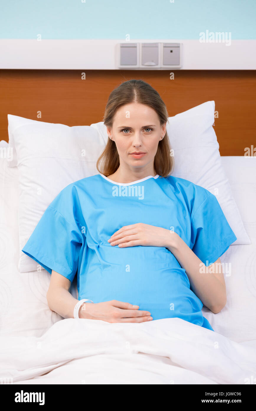 caucasian pregnant woman lying in hospital bed and looking at camera ...