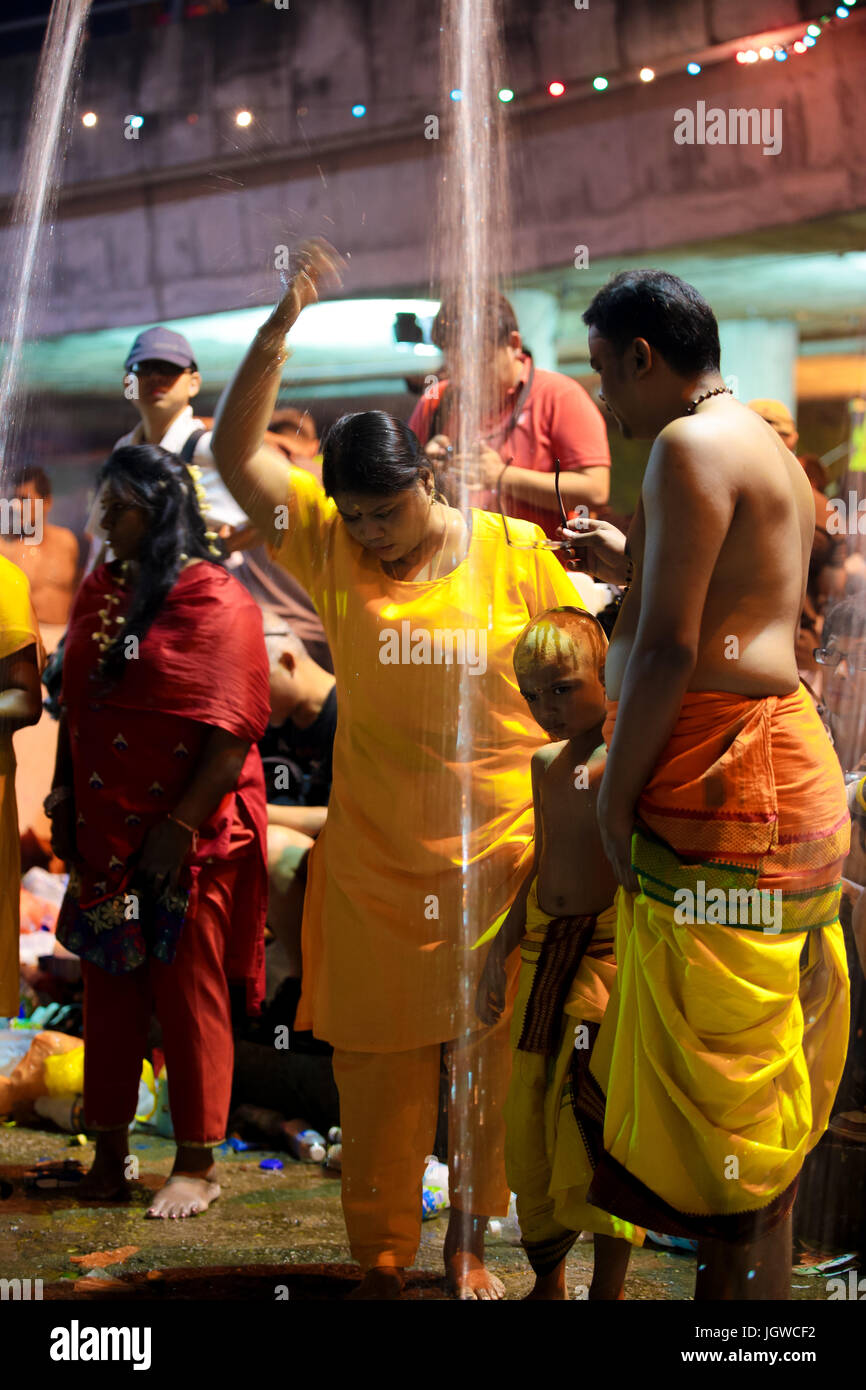 Hindu family taking shower before their kavadi walk to batu cave temple ...