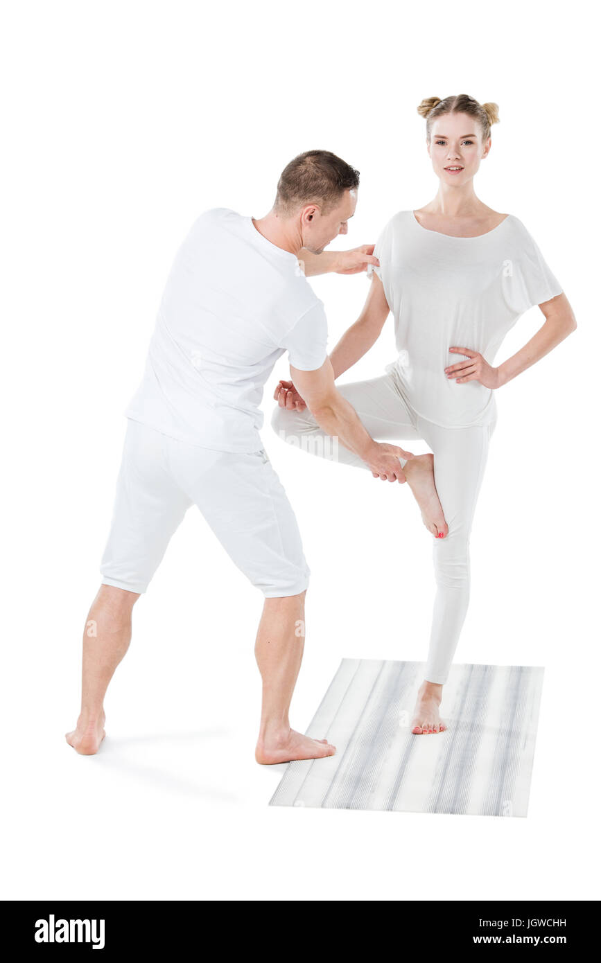 attractive blonde woman practicing tree yoga pose with trainer isolated ...