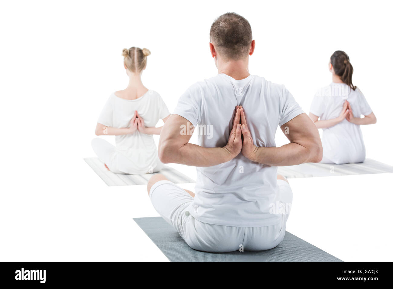 Back view of sporty young people sitting in lotus position with namaste ...