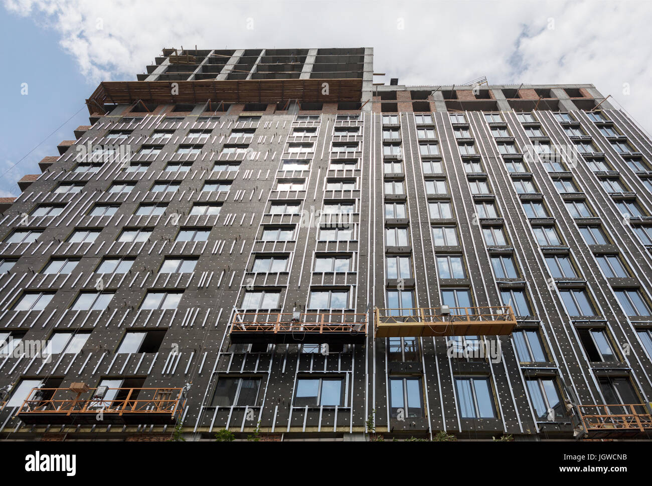 In the windows of the facade of a high-rise building under construction ...