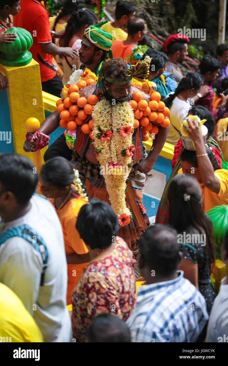 Hindu pilgrim with fruit kavaldi and flower garland climbing the batu ...