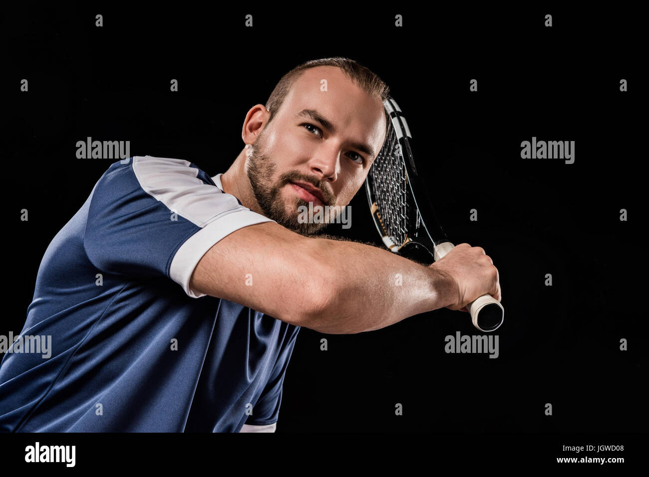 Focused young sportsman playing tennis isolated on black Stock Photo ...