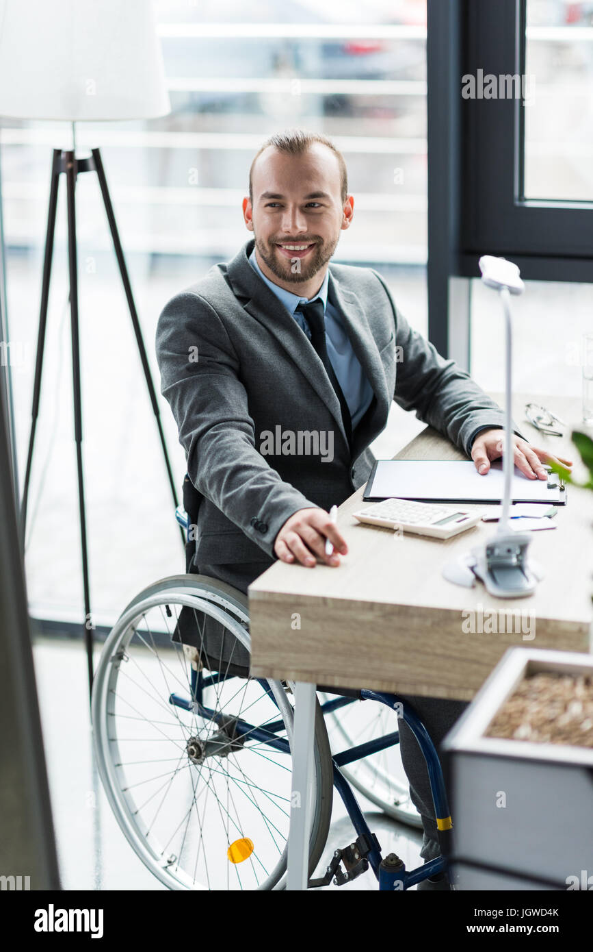 smiling physically handicapped businessman in suit on wheelchair ...