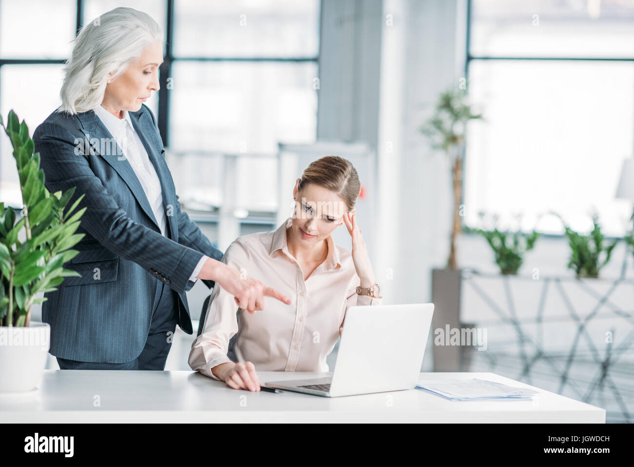 young stressed businesswoman and her boss working with laptop computer ...