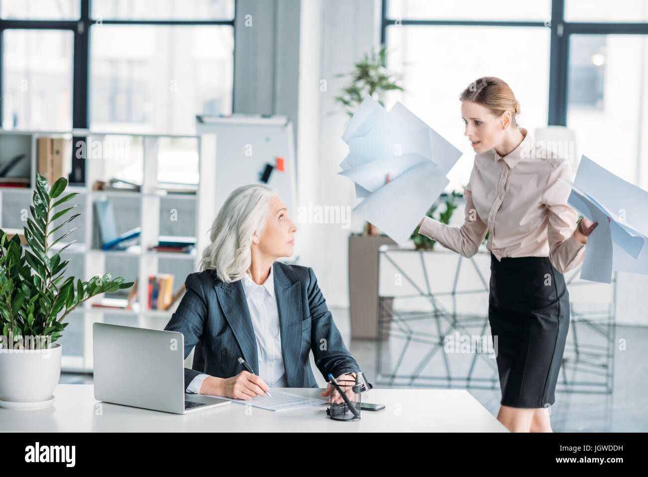 young stressed businesswoman with documents arguing at colleague ...
