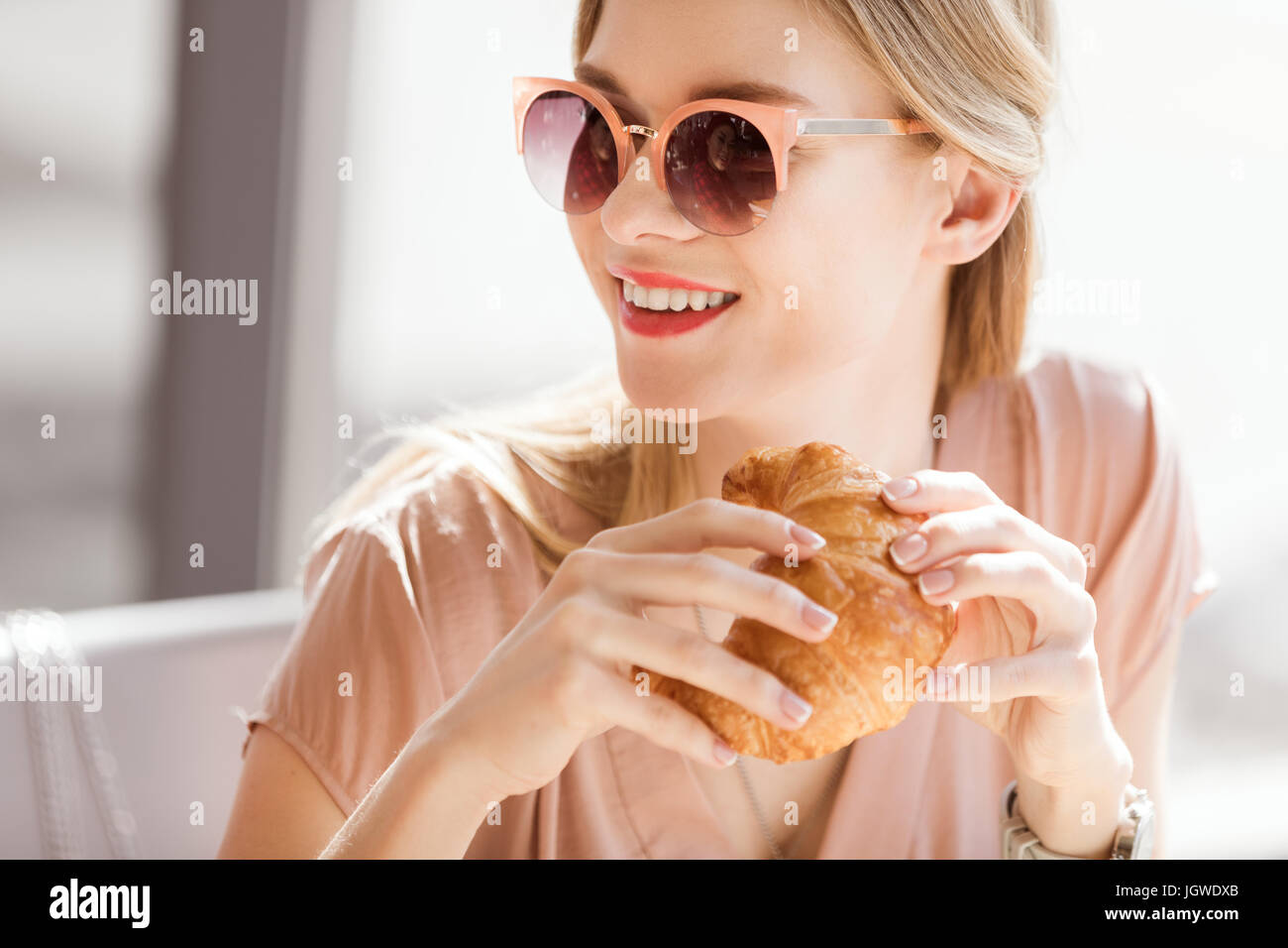 young woman eating croissant while sitting in cafe, coffee break Stock ...