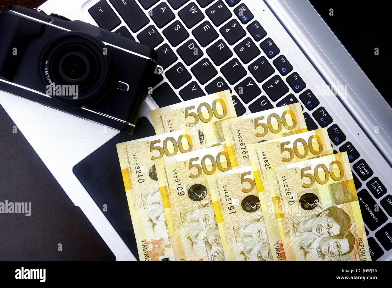 Photo of a camera and Philippine peso bills on a laptop computer ...