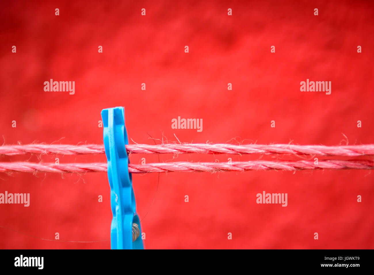 Vintage view of Blue Clothes peg pinned to a bench with red wall in a ...