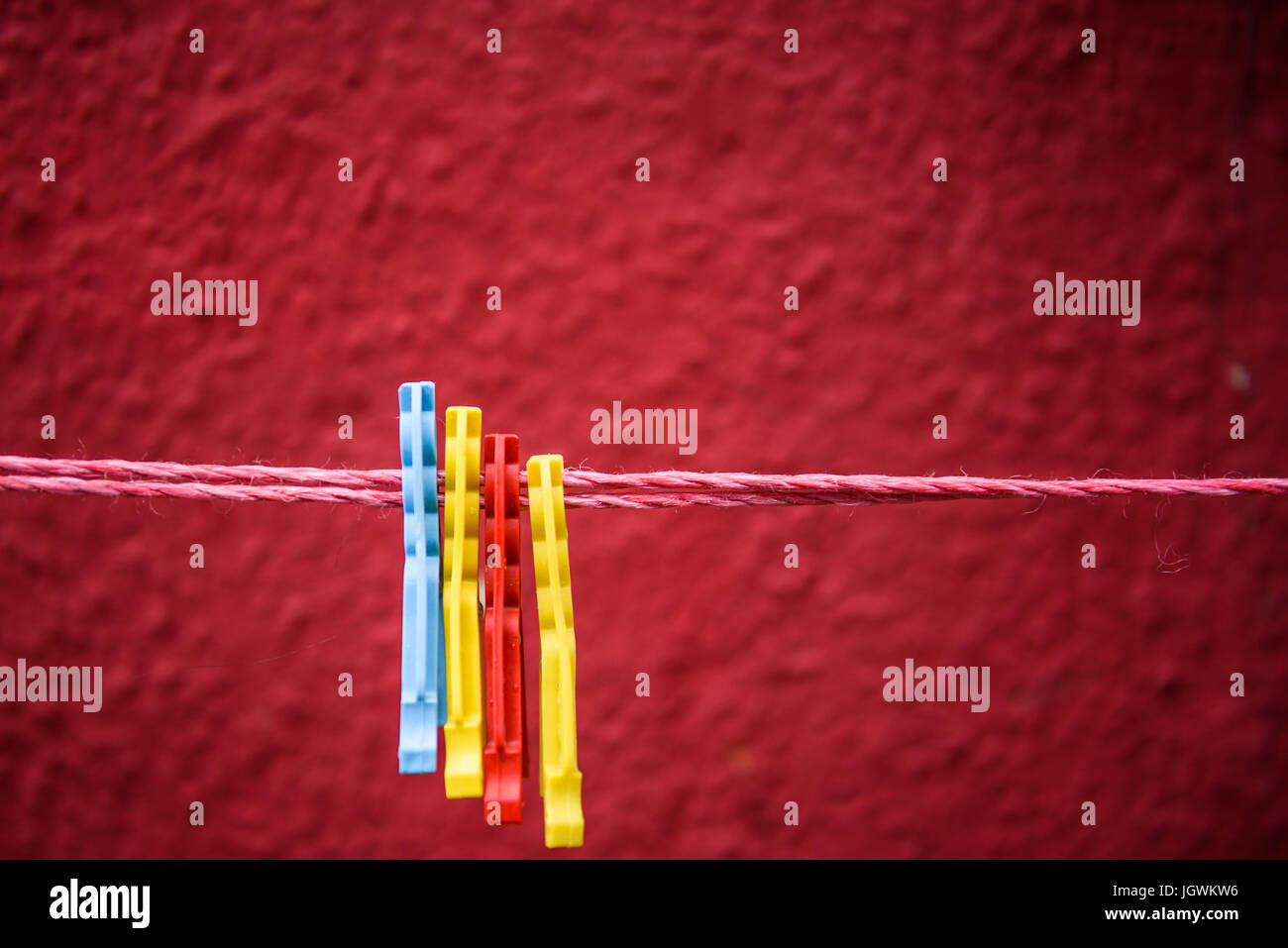 Vintage view of yellow Clothes pegs pinned to a bench with red wall in ...