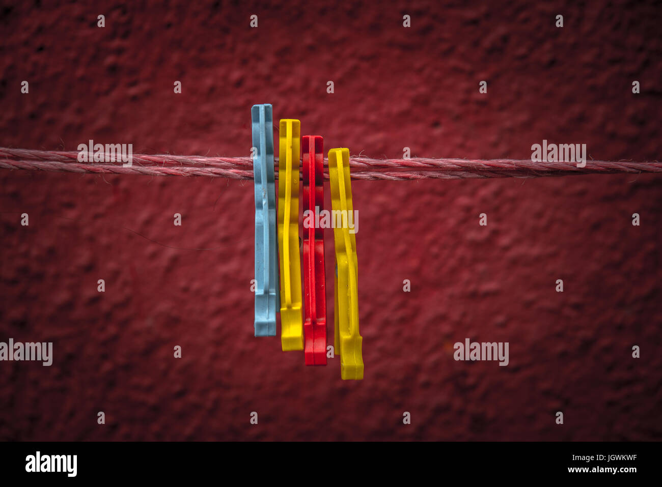 Vintage view of purple Clothes pegs pinned to a bench with red wall in ...