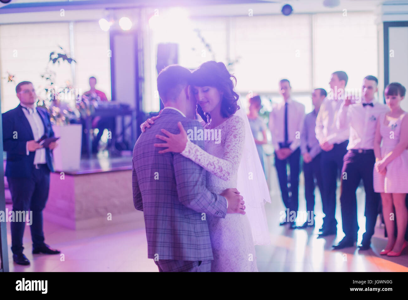 The smiling newlywed couple is hugging during their first dance in the ...