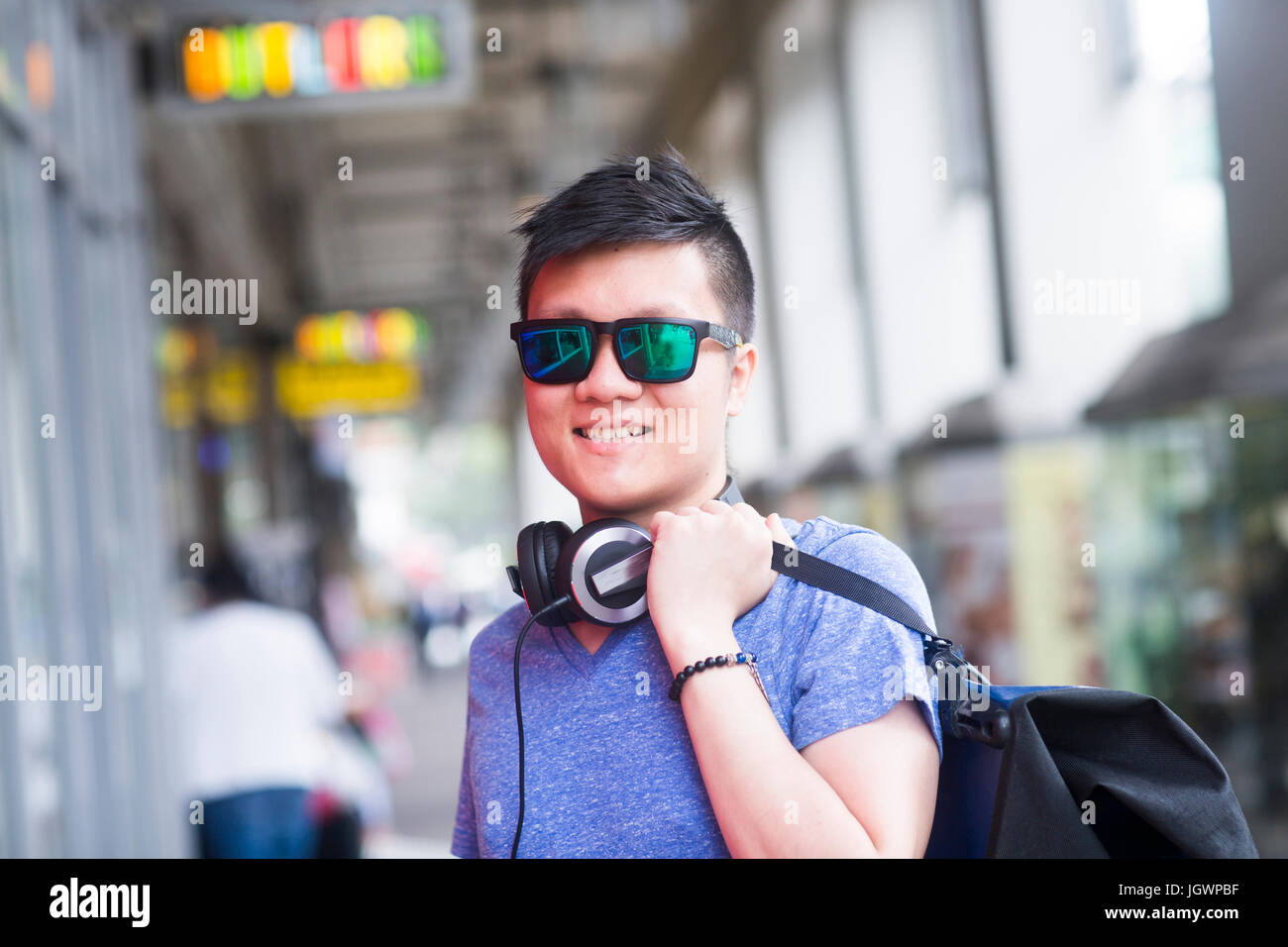 Portrait of man with headphone wearing sunglasses looking at camera ...