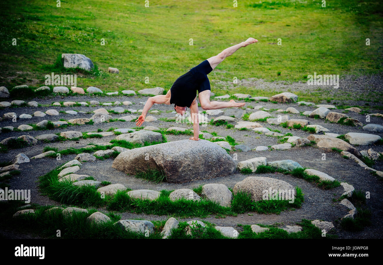 Acrobat performing on stone arrangement, Bainbridge, Washington, USA ...