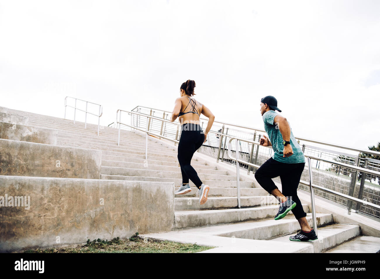 Man and woman exercising outdoors, running up steps, rear view, South ...