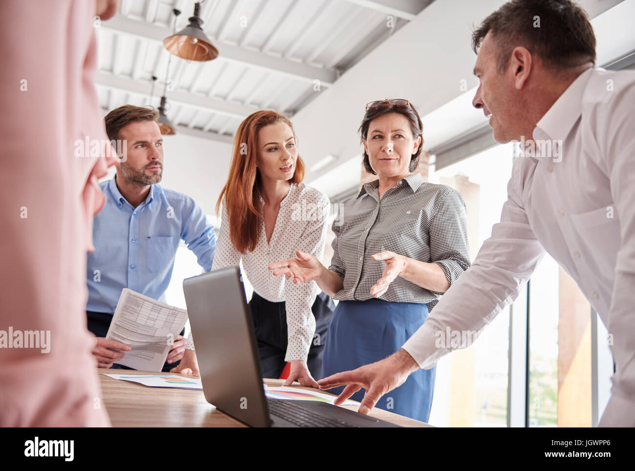 Colleagues in office with laptop having discussion Stock Photo - Alamy