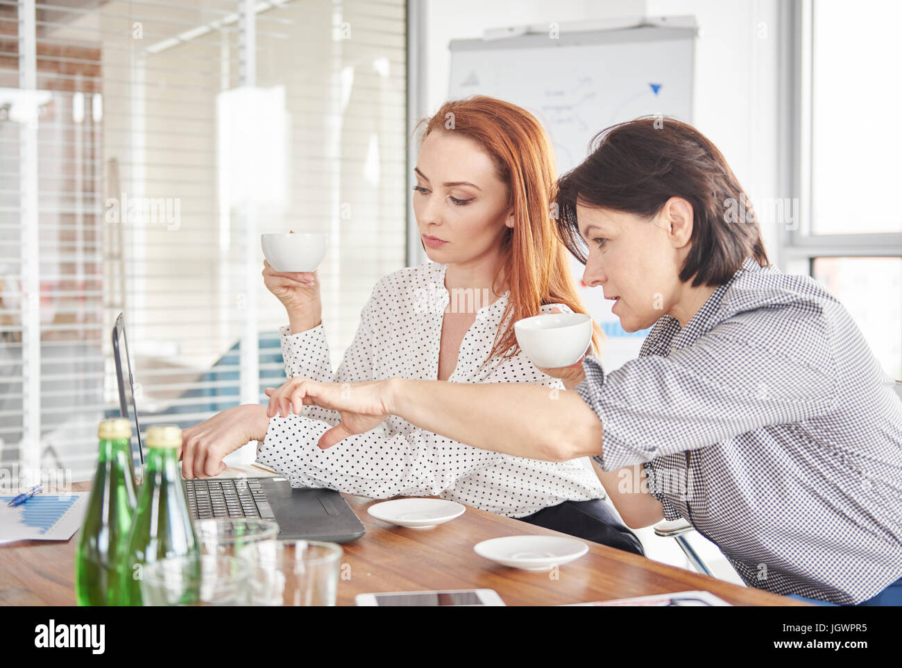 Businesswomen with coffee having discussion in meeting Stock Photo - Alamy