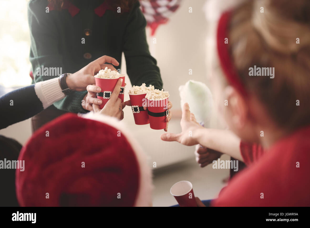 Cropped shot of young woman handing out popcorn at christmas party ...