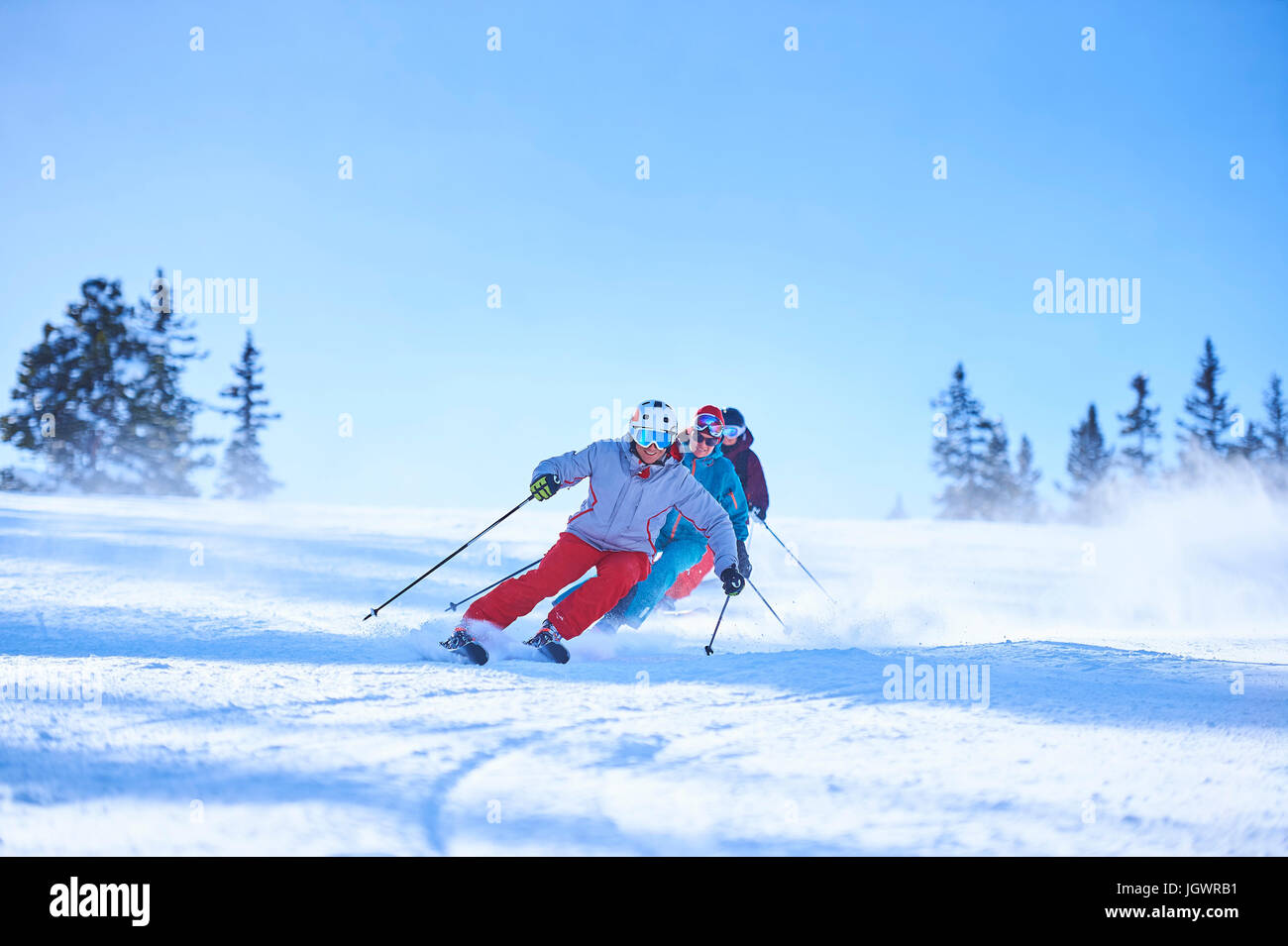 Row of male and female skiers skiing down snow covered ski slope, Aspen ...