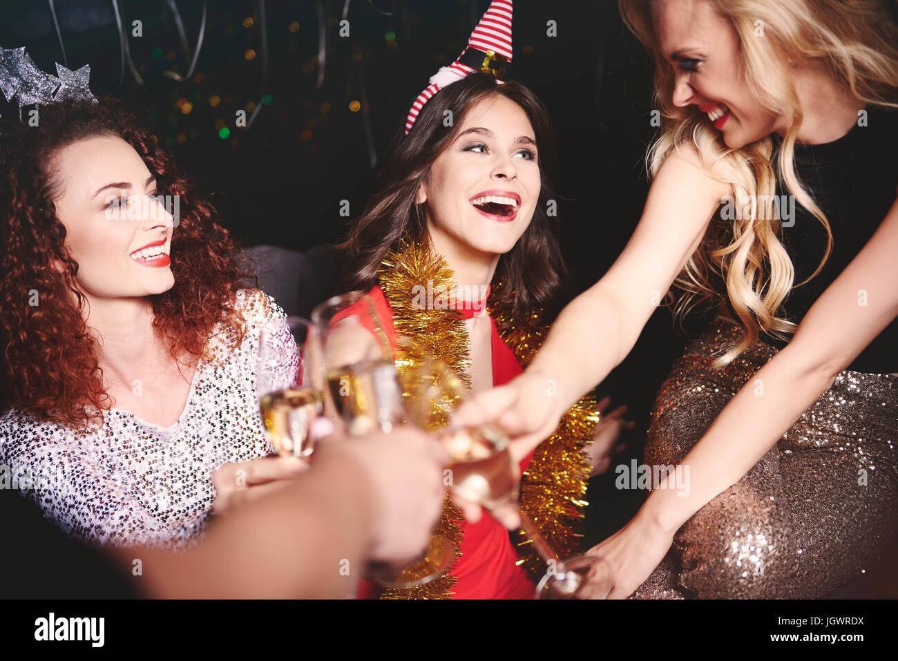 Three women sitting together at party, holding champagne glasses ...