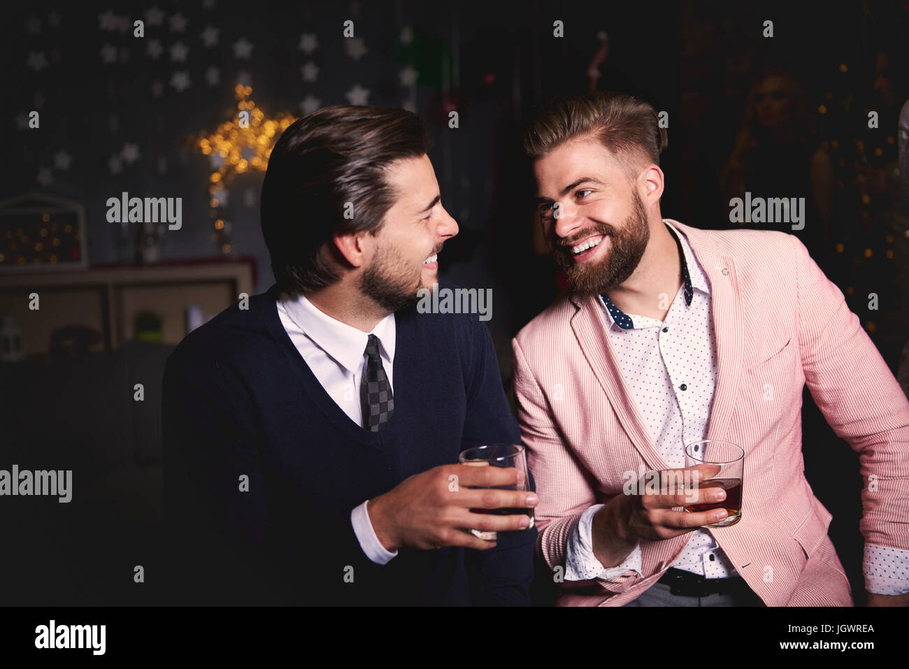 Two men at party, holding drinks, laughing Stock Photo - Alamy