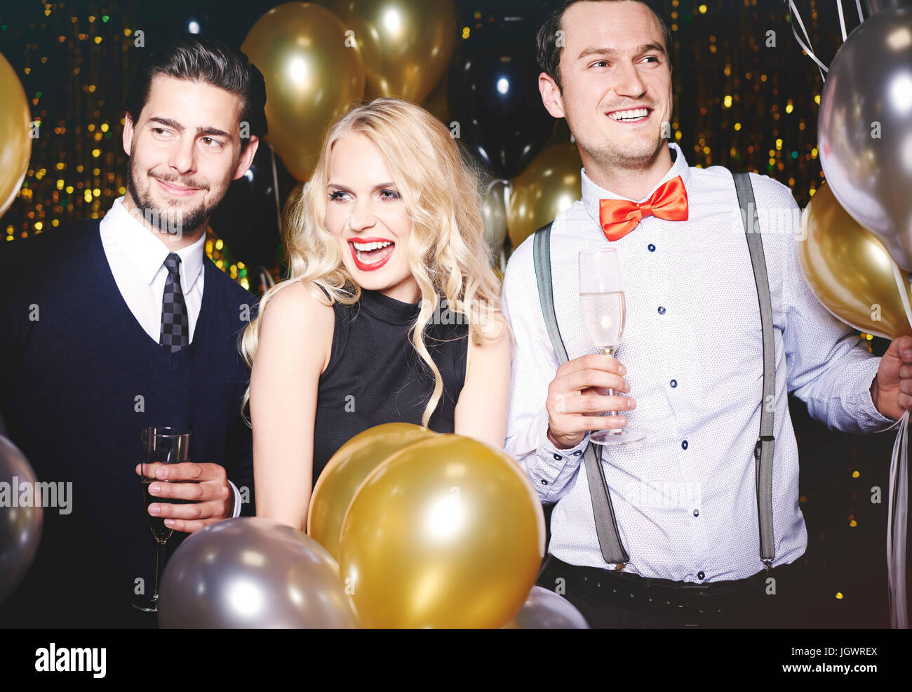 Portrait of three people at party, surrounded by balloons, holding ...