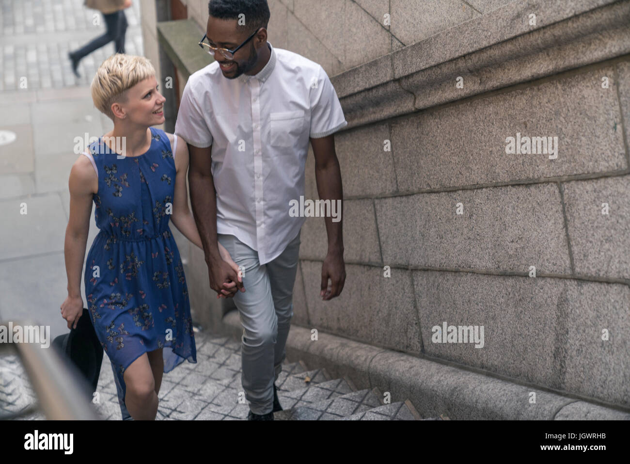 Young couple walking up steps, hand in hand, smiling Stock Photo - Alamy