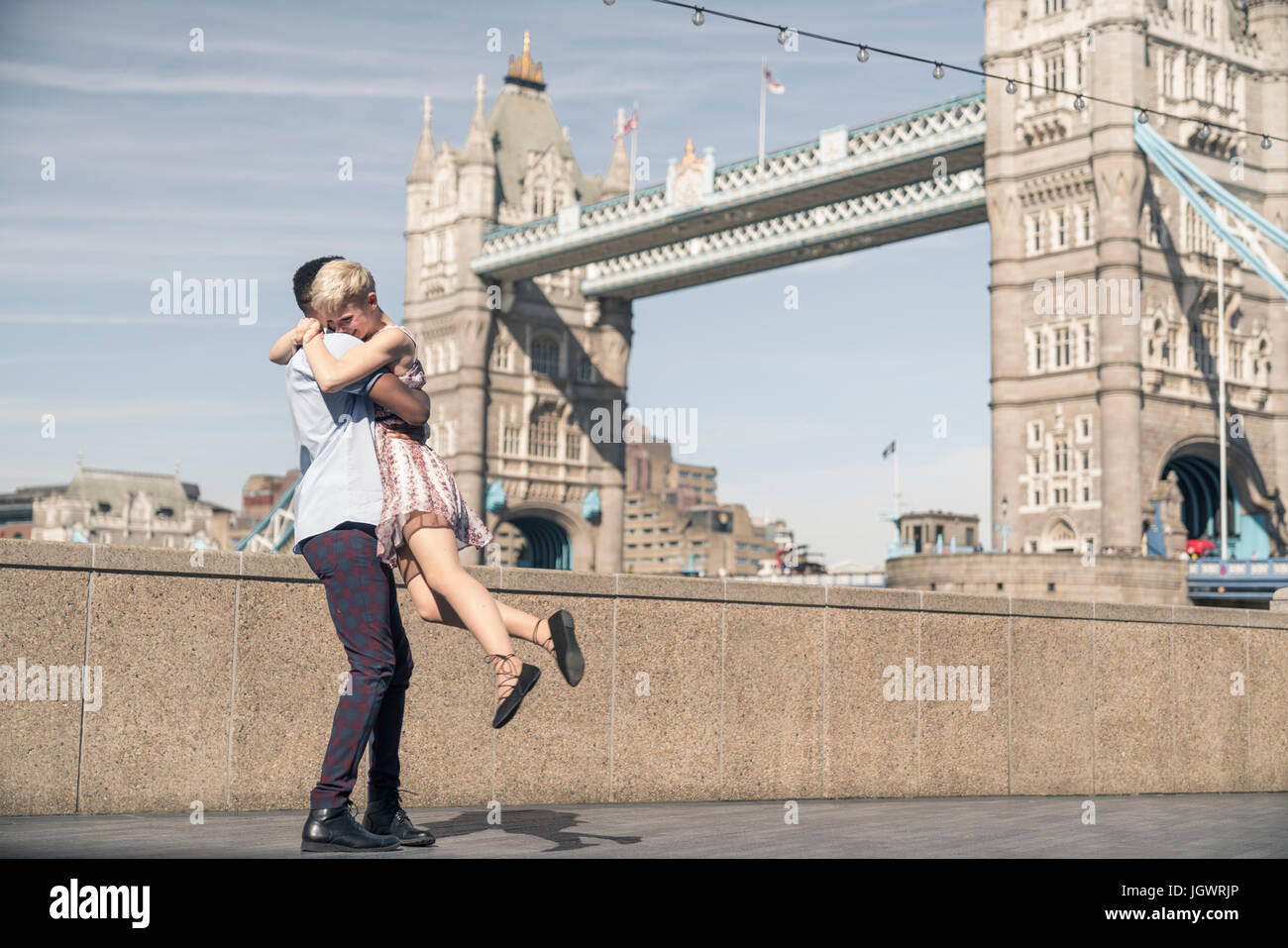 Young couple hugging outdoors, Tower Bridge in background, London ...