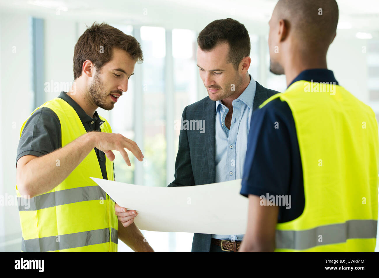 Construction workers and businessman, looking at plans Stock Photo - Alamy