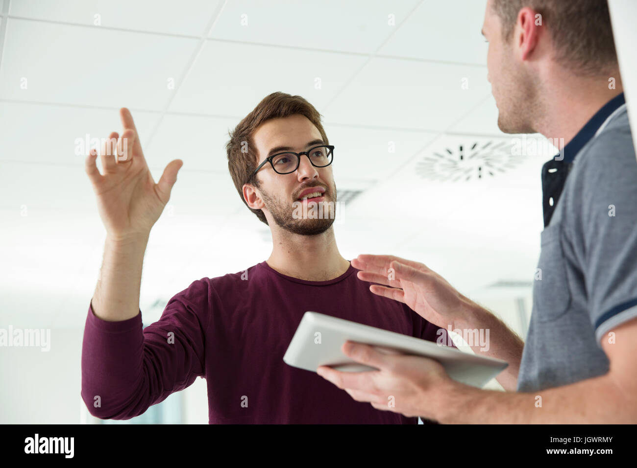 Two men, having conversation, holding digital tablet Stock Photo - Alamy