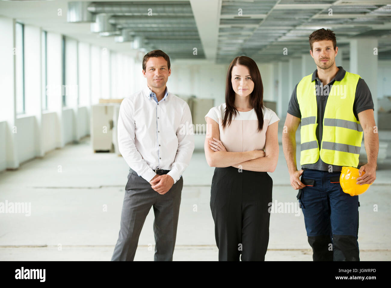 Portrait of three workers, standing in newly constructed office space ...